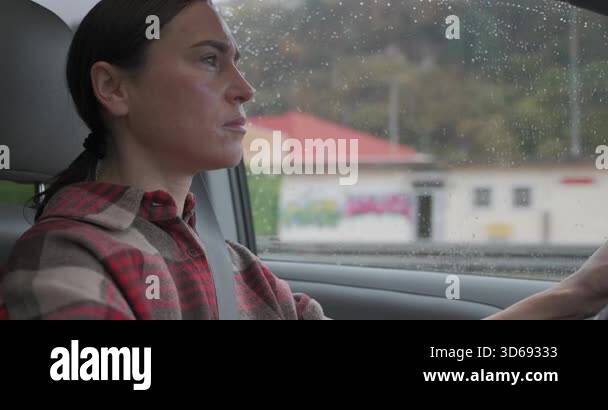 Over the shoulder view of a woman driving a car during heavy rain ...