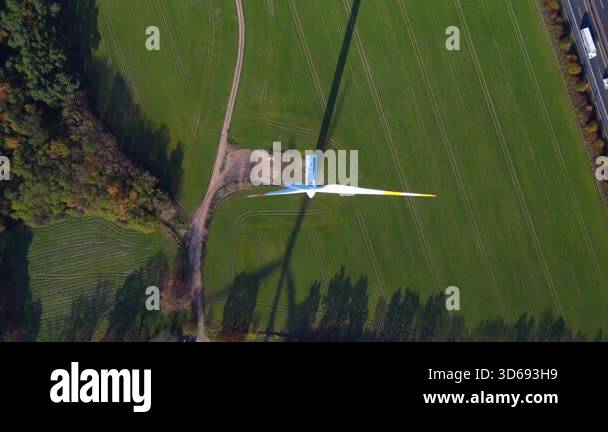Wind turbine standing in green field next to highway autobahn in autumn ...
