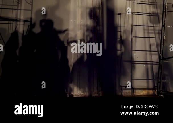 Footage of shadows of dancers and stage crew projected on a backstage ...