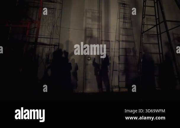 Footage of shadows of dancers and stage crew projected on a backstage ...