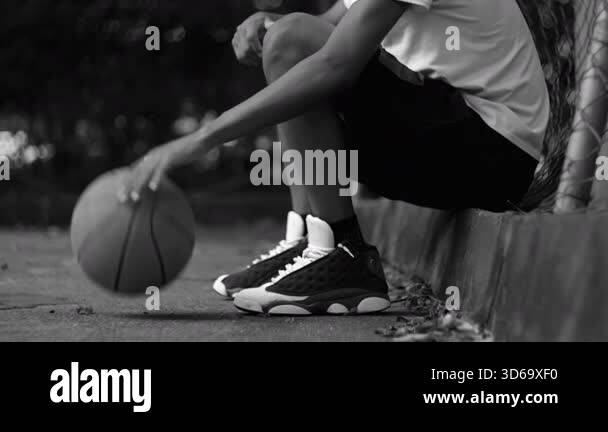 African American man sitting by fence on outdoor basketball court ...