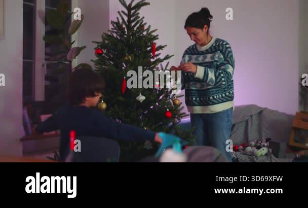 Mother and child decorating Christmas tree together at home, sharing ...