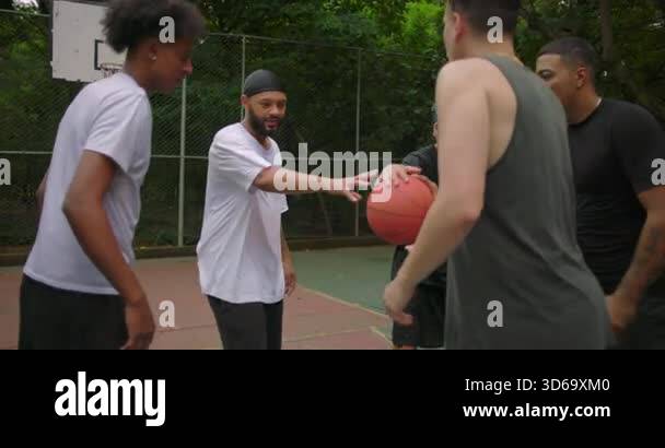 Group of Hispanic and African descent men joining hands over basketball ...