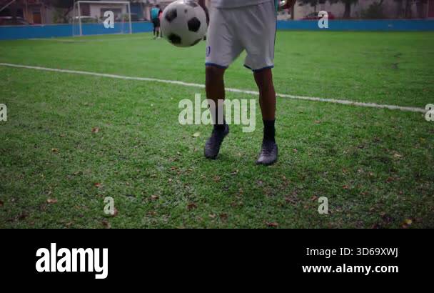 African American Latin man practicing kick-ups on soccer field, balancing ball with precision ...