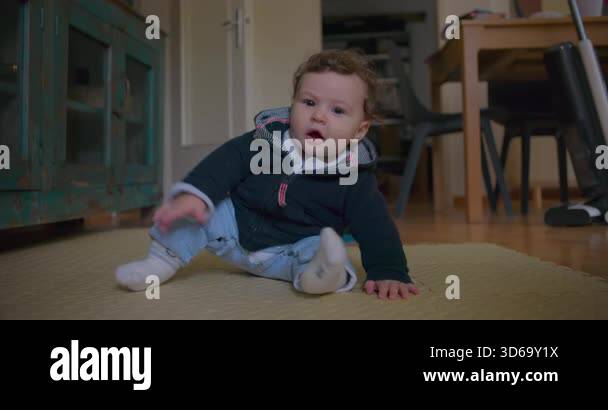 Baby sitting upright on floor looking attentively ahead, expressive ...
