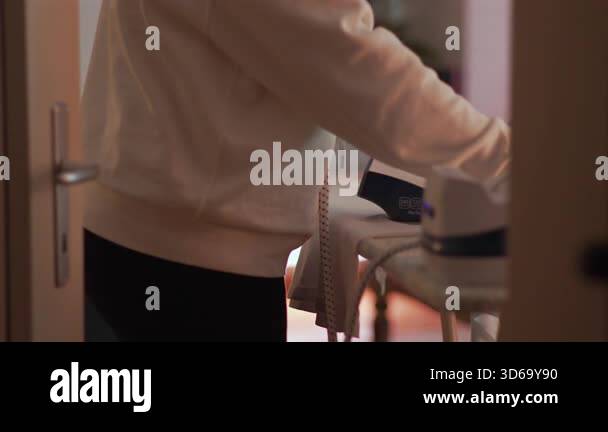 Woman ironing clothes at home, daily household routine showing care and ...