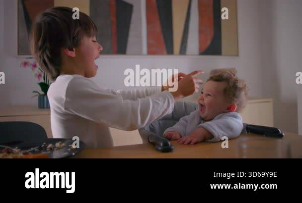 Older brother making baby laugh at home, joyful sibling interaction ...