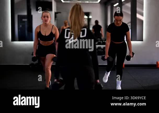 Three women engage in a strength training workout in a modern fitness studio. They focus on ...