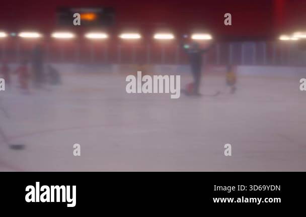 Blurred view of young hockey player in red and yellow uniform standing ...