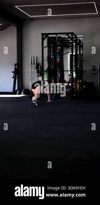 A person performs mountain climbers in a sleek gym with black flooring ...