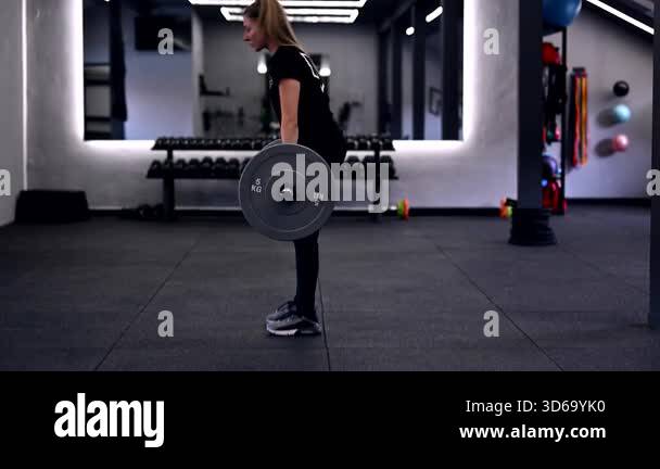 A woman focuses on her lifting technique while performing deadlifts at ...