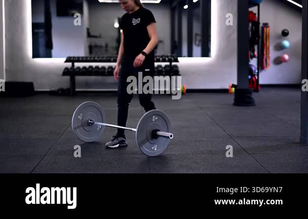 In a modern gym, a trainer demonstrates proper deadlift technique while ...