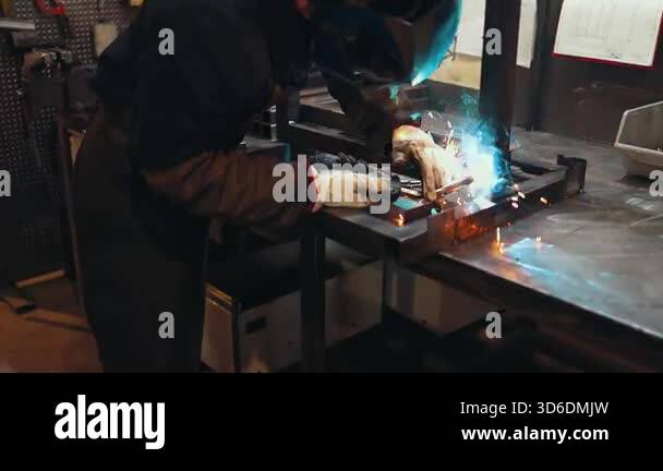 Industrial worker wearing a protective mask and gloves welding a metal ...