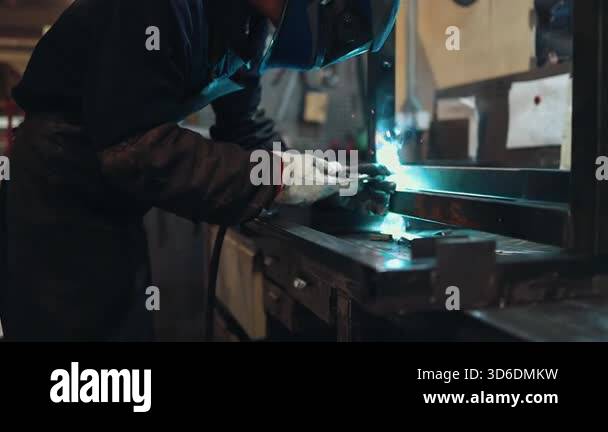 Industrial worker wearing a protective mask and gloves welding a metal ...