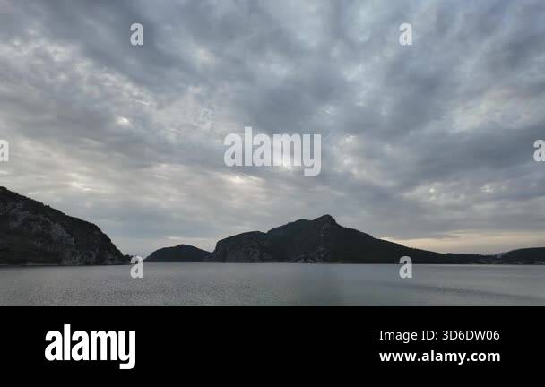 Time-lapse capturing the sun setting behind mountain silhouettes under ...