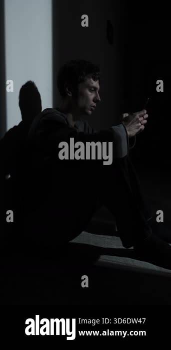 Man sits alone in the dark, focused on tense texting during ...