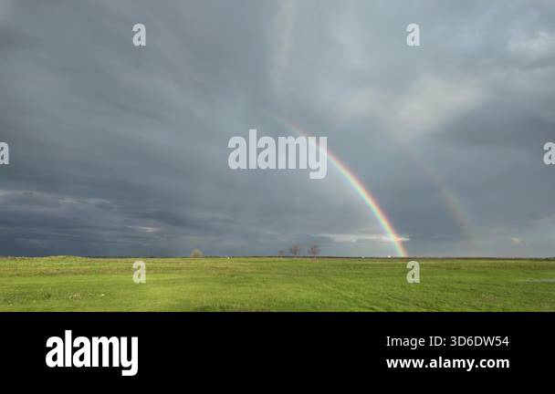 Time-lapse video showing a double rainbow forming above a green meadow ...