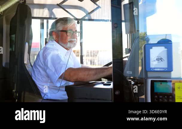 Experienced senior male bus driver with a beard and glasses maneuvering ...