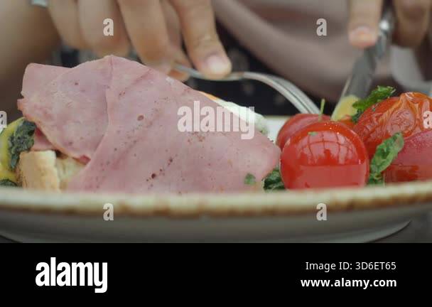 Enjoying a hearty breakfast featuring ham, eggs, and fresh tomatoes ...