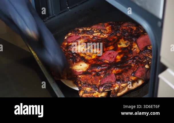 Removing a burnt pizza from the oven and assessing the damage Stock ...
