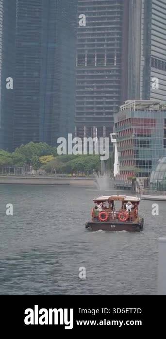 A small tour boat moves across the water near the citys tall buildings ...