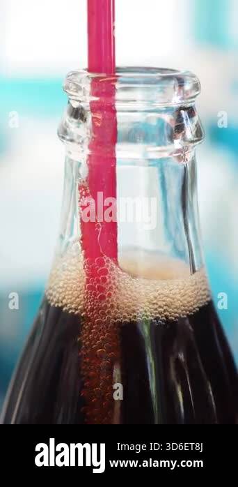 A close look at a soda bottle filled with fizzy drink and a straw Stock ...