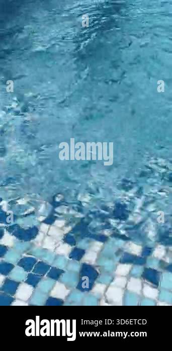 Clear blue swimming pool with sunlight reflections on water surface ...