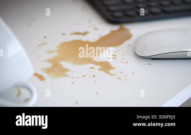 Coffee has spilled on the desk, making a mess near the keyboard Stock ...