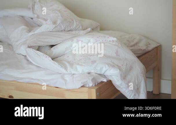 A cozy bedroom with a messy bed and soft bedding early in the morning ...