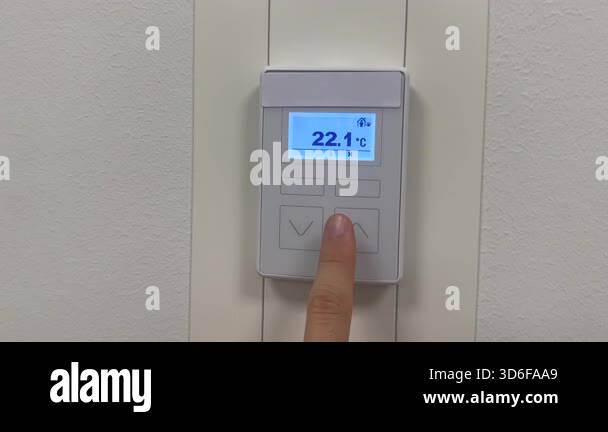 A modern digital smart thermostat mounted on a wall, displaying active ...