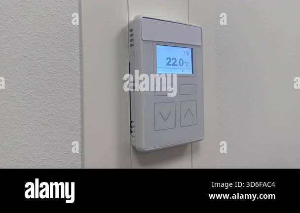 A modern digital smart thermostat mounted on a wall, displaying active ...