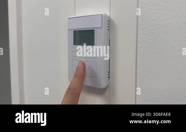 A modern digital smart thermostat mounted on a wall, displaying active ...