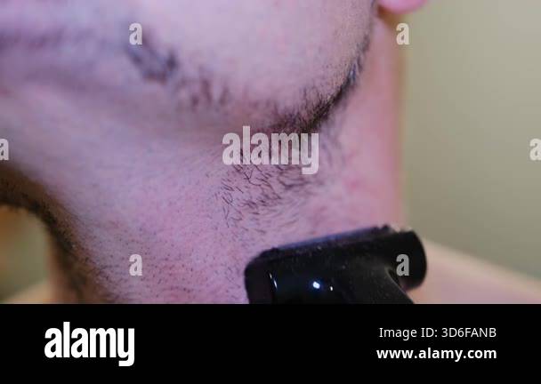 Close-up macro footage of man shaving beard with electric trimmer ...