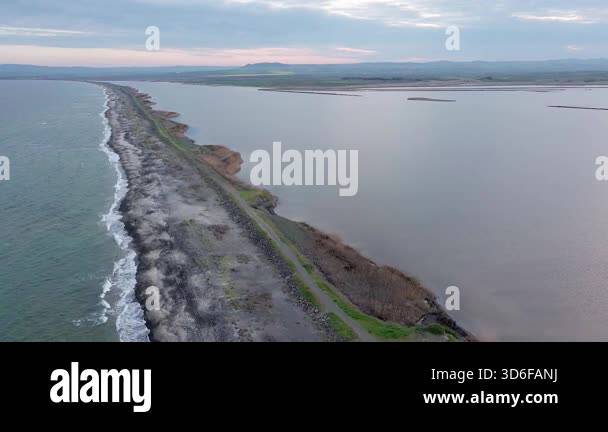 Birds eye view of narrow empty quiet beach with dry sand right and ...