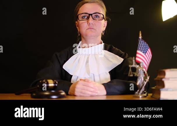 Female judge in traditional robe with white collar sitting at a desk ...