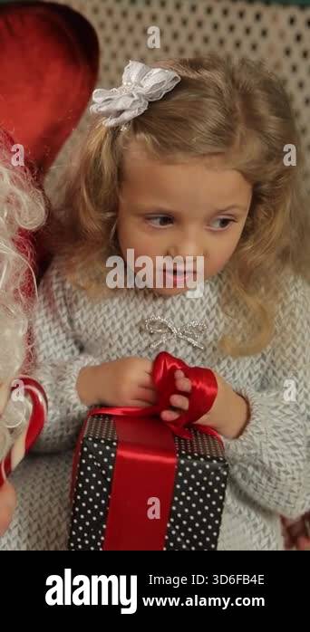 Cute little girl holding a wrapped Christmas present while standing ...