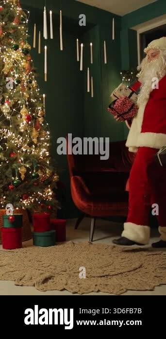 Santa Claus quietly delivering presents under a decorated Christmas ...