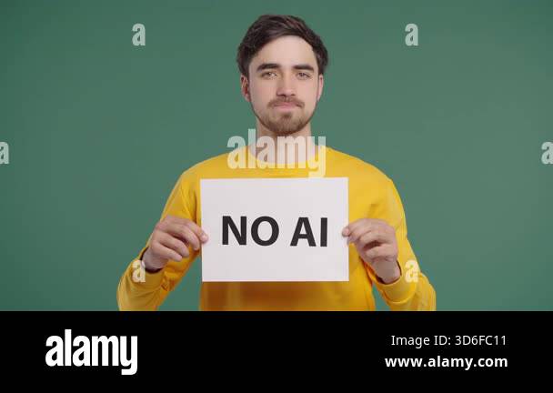 Young Man standing on green wall, holding handmade sign NO AI. Sad ...