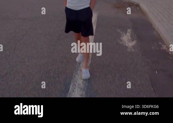 teen balancing on painted road line with hands in pockets, walking down ...
