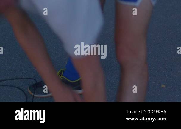 man adjusting jump rope before workout on pavement, bending to set rope ...