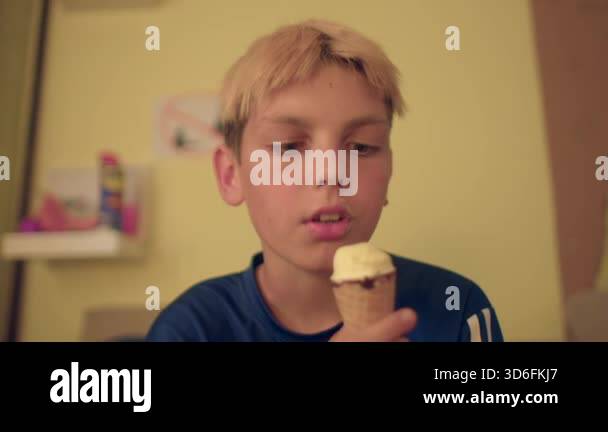 white blond teen eating ice cream, slow close-up in small bedroom ...