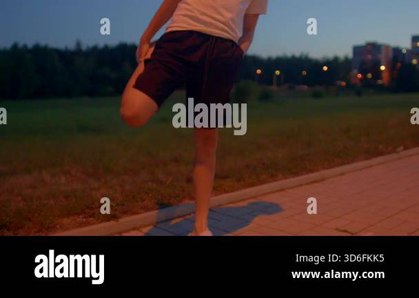 white teen runner stretching on path dusk one leg balance warmup ...