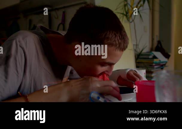 young man leaning over table inspecting red container and preparing ...