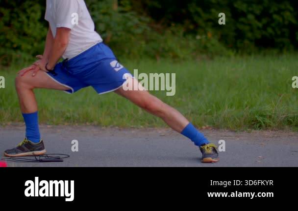 white male lunge stretch on roadside focusing on hamstring calf ...