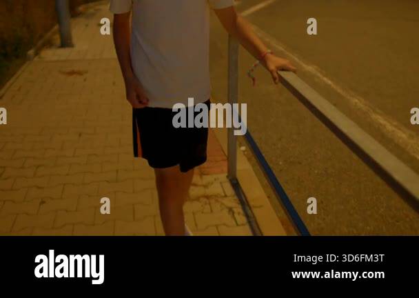 night walkway hand on railing, white person walking along curb using ...