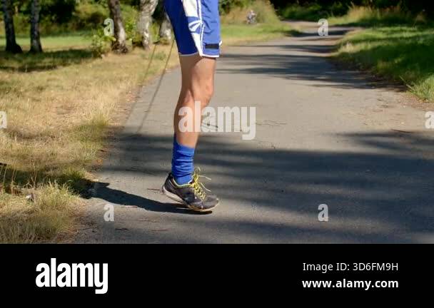 man retrieves jump rope, man leans down to grasp jump rope on shaded ...