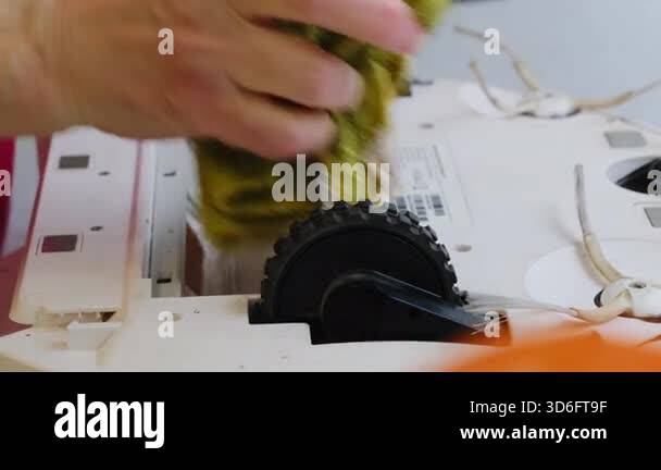 Adult woman cleans robotic wheel zone using yellow cloth near base ...