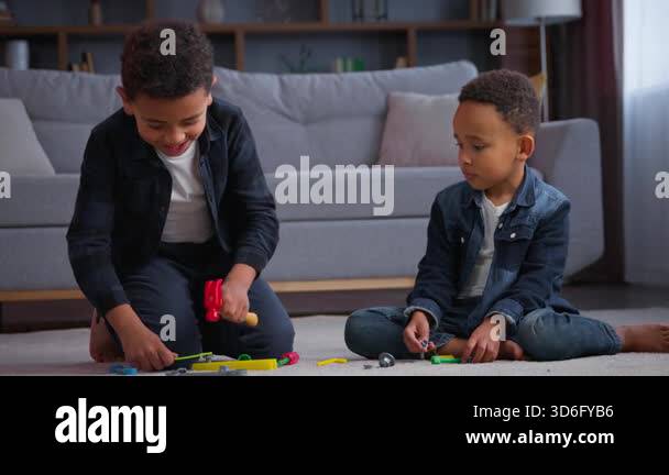 Two African American children playing with plastic toys at home ...