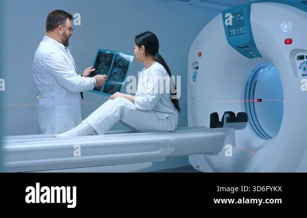 Doctor making analysis of MRI scanning. Doctor holding tomography scan and talking to patient ...