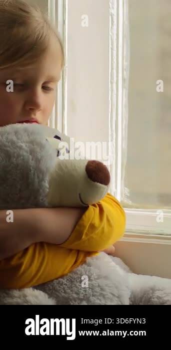 Stressed little girl child looking at window hugging teddy bear toy ...